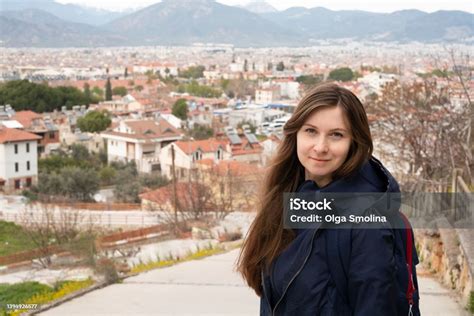 빨간 지붕이있는 집 사이에서 아름다운 도시를 여행하는 긴 머리카락을 가진 예쁜 중년의 갈색 머리 여인 웃고 카메라를보고 여행 유럽의 도시에서 관광 하이킹 항해 개념 30