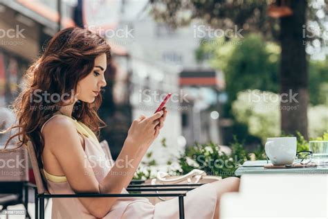 카페에서 커피 한잔과 함께 테이블에 앉아있는 동안 스마트폰 사용 하는 젊은 여자의 모습 뜨거운 음료에 대한 스톡 사진 및 기타 이미지 뜨거운 음료 마실 것 무선 기술