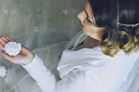 室内穿着婚纱的女人手里拿着一朵白玫瑰