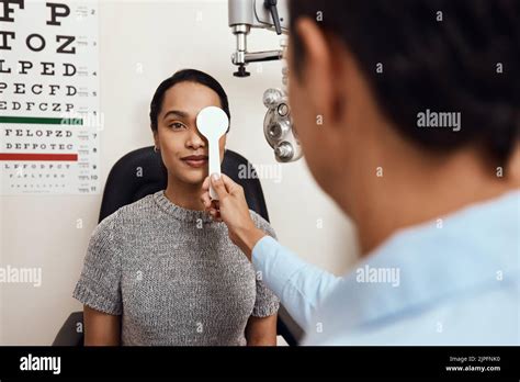 Eye Exam Vision Testing At An Optometrist With Young Woman And Doctor Opthamologist Using An