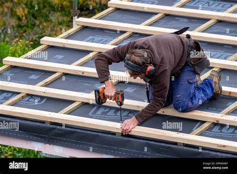 Tradesman Fastening Timber Roof Battens Over Insulation On A Home