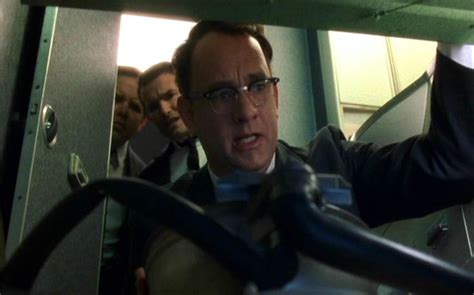 A Man In Suit And Tie Riding On Top Of A Bus With Other People Behind Him