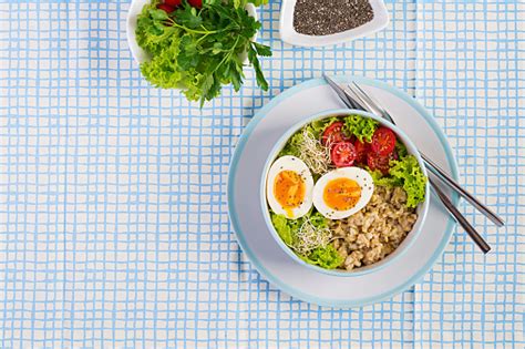 신선한 샐러드 오트밀 토마토 양상추 마이크로 그린 및 삶은 달걀과 함께 아침 식사 그릇 건강 한 음식 채식 부처 그릇 평면도 평