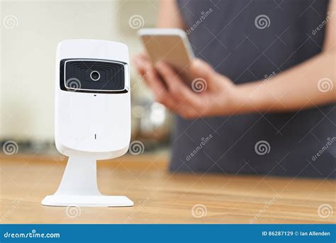 Woman Controlling Smart Security Camera Using App On Mobile Phone Stock