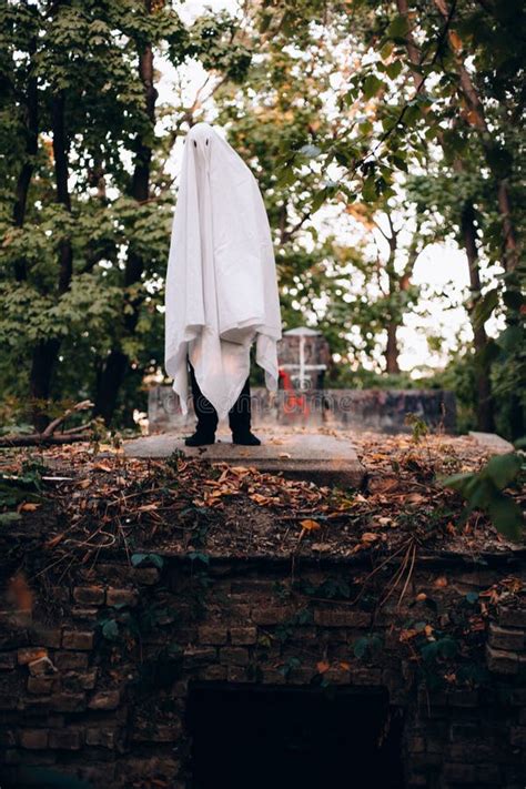 Man Wearing Ghost Costume While Standing On The Grave In The Cemetery