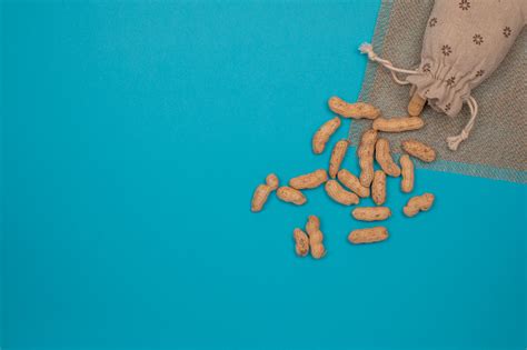 견과류 껍질을 벗긴 땅콩 린넨 가방 색깔배경에서 테이블에 뿌려 카피 스페이스가있는 상단보기 평평한 누워 건강에 좋지 않은 음식에