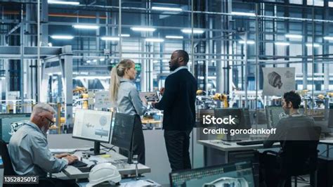 자동차 공장 사무실 자동차 엔지니어 팀이 작업 토크 태블릿 컴퓨터를 사용하여 첨단 엔진을 위한 고급 3d 모델을 설계합니다 자동 로봇 암 조립 라인 제조 차량 엔지니어에