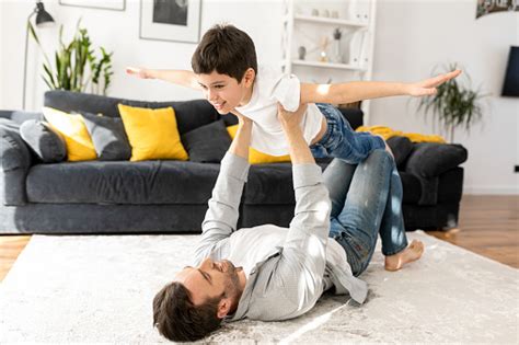 사랑스러운 아버지는 소니와 놀아요 행복한 아버지와 학령기 아들은 집에서 함께 시간을 보내고 아늑한 거실에서 바닥에 누워있는