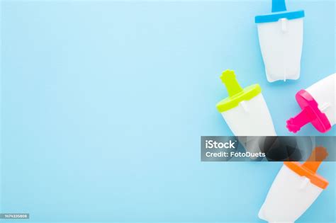 화려한 막대기에 수제 아이스 캔디를 위한 흰색 플라스틱 용기 밝은 파란색 테이블 배경입니다 파스텔 색상 근접 촬영 여름에는