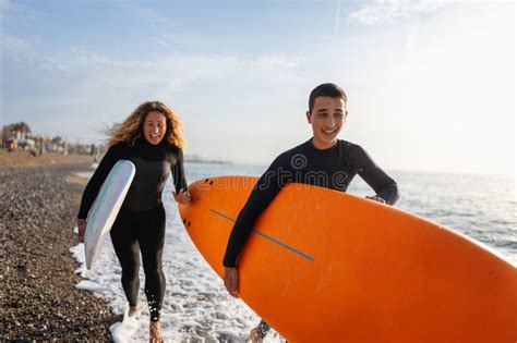 Fit Couple Surfing At Sunset Friends Having Fun Inside Ocean Extreme Sport And Vacation