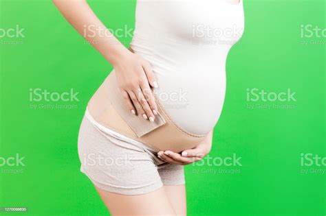 特寫孕婦在支援繃帶對背痛在綠色背景與複製空間母親背痛骨科腹部支撐帶概念 照片檔及更多 25歲到29歲 照片 25歲到29歲 一個人