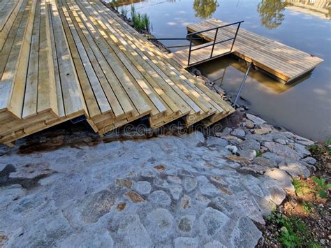 A Floating Jetty For Mooring Ships Is Fixed With Metal Rods On Hinges Wooden Stairs Are Benches