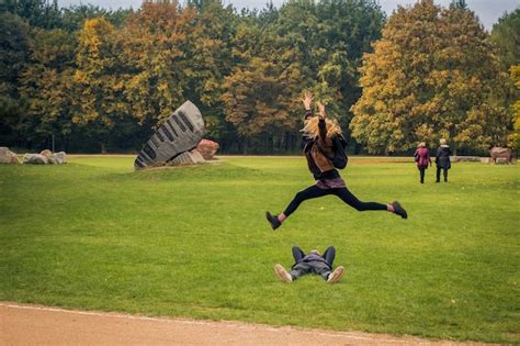 Premium Photo Full Length Of Woman Jumping Over Man At Park
