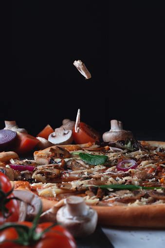 햄 토마토 치즈 양파 허브가 있는 커팅 우드 보드에 수제 이탈리아 피자에 떨어지는 버섯 조각이 어두운 돌 슬레이트 테이블에 놓여 있습니다 구도에 대한 스톡 사진 및 기타