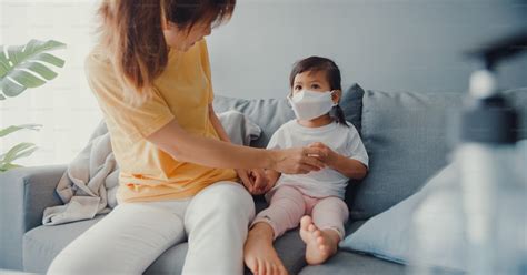 보호용 안면 마스크를 쓴 행복한 아시아 가족 엄마는 집 거실의 소파에 앉아 있다 함께 시간 보내기 사회적 거리두기 코로나바이러스 예방을 위한 격리 의료 개념 사진