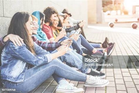 천년 친구 스마트폰 앉아 야외를 사용 하 여 다양 한 문화 사람들이 중독 새로운 기술 동향청소년 사회 생활과 우정의 개념여자 얼굴에 초점 공동체에 대한 스톡 사진 및 기타