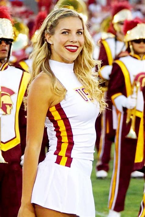 A Cheerleader Is Standing In Front Of Other Cheerleaders At A Football Game