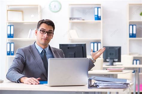 موظف رجل أعمال وسيم يجلس على مكتبه في المكتب المتجه الخلفية والصورة