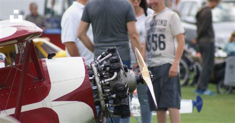 회색 크루 넥 티셔츠를 입은 남자가 빨간색과 흰색 로봇 옆에 서 있습니다 사진 Unsplash의 무료 사람의 이미지