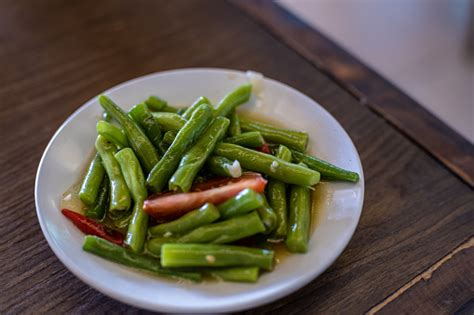 Sayur Tumis Kacang Panjang 또는 긴 콩의 소스 야채는 나무 판자에 흰색 접시에 제공되는 전형적인 인도네시아