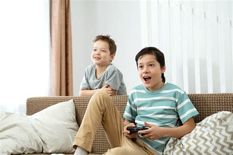 두 명의 흥분한 형제가 거실소파에서 집에서 조이스틱으로 비디오 게임을 합니다 재미 있는 소년 엔터테인먼트 가족 레저 12 13세에 대한 스톡 사진 및 기타 이미지 Istock