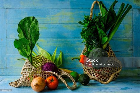 많은 다채로운 컬러 샐러드 야채는 오래 된 파랑에서 매달려 재사용 가능한 문자열 황 마 가방에 대비 하 고 녹색 추상적인 나무 패널 배경 벽 아래 같은 색된 테이블에 가방에