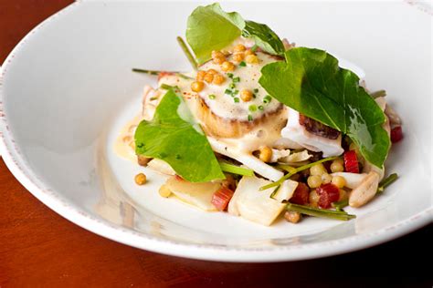 가리비 마늘 버터 샬롯 화이트 와인에 구운 팬 클래식 한 해산물 고급 식사 앙트레 찐 유기농 채소 브로콜리 당근 콜리플라워 레몬과 이탈리아 파슬리로 장식되어 제공됩니다 0