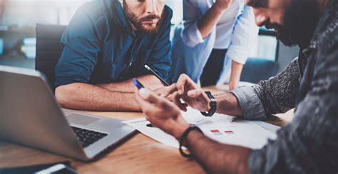팀워크 개념입니다 현대 Coworking 스튜디오에서 함께 일 하는 3 명의 동료의 그룹 수염 난된 남자 스마트폰 보여주는