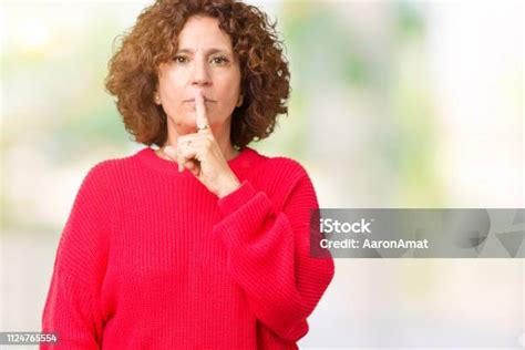 아름 다운 중간 거 시 수석 여자 입술에 손가락으로 조용한 것을 요구 하는 고립 된 배경 위에 빨간 겨울 스웨터 침묵 및 비밀 개념입니다 갈색 머리에 대한 스톡 사진 및