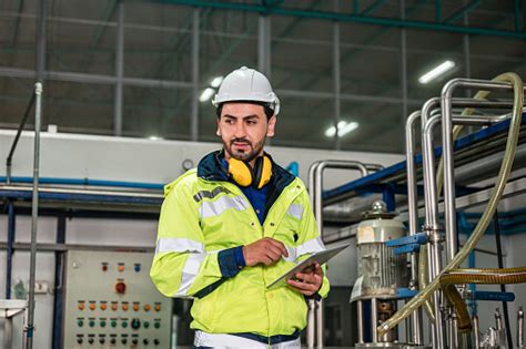 공장에서 생산 라인에서 태블릿 검사 및 제어 보일러 탱크 및 액체 파이프 라인과 유니폼을 입은 백인 기술자 엔지니어 식품 가공