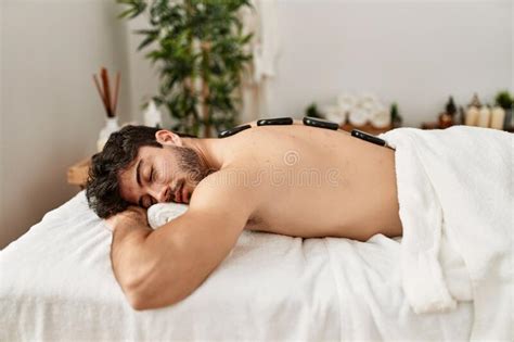 Man Reciving Back Massage With Black Stones At Beauty Center Stock