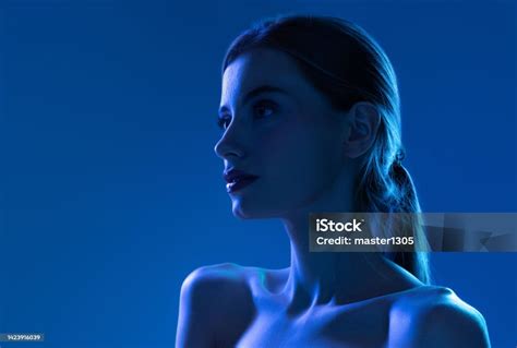 파란색 그라디언트 스튜디오 배경에 네온 라이트에서 여성 패션 모델의 초상화 트렌디 한 메이크업과 잘 보관 된 피부를 가진