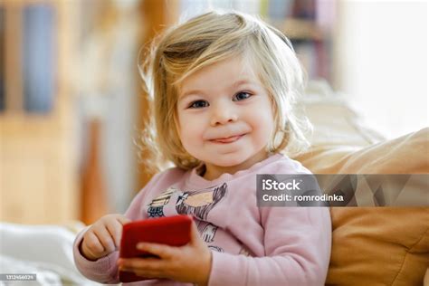 집에서 스마트 폰으로 노는 귀여운 어린 유아 소녀 건강한 아기손가락으로 전화를 건드리고 만화를 찾고 교육 용 게임을 재미있게