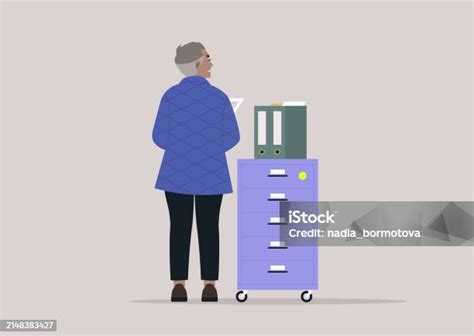 현대적인 사무실 환경에서 파일을 정리하는 직원 한 사람이 파일 캐비닛 옆에 서서 직장에서 문서를 분류하고 있습니다 노인에 대한