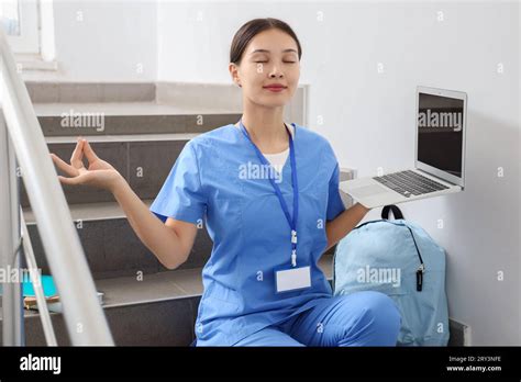 Asian Medical Intern With Laptop Meditating On Stairs At University