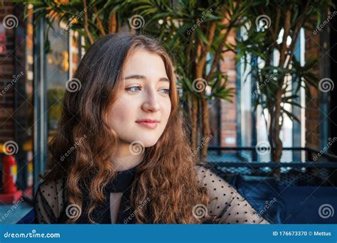 A Girl With Long Brown Hair Looks Out The Window Thoughtfully Stock
