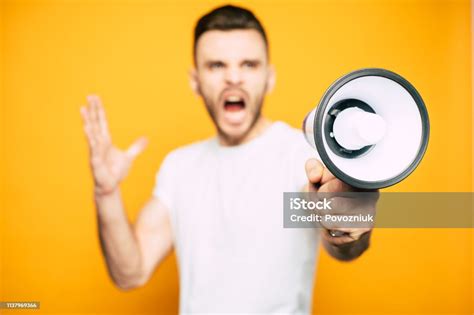 주의 집중 기간 단순한 흰색 티셔츠에 노란 벽 근처에 있는 남자가 그의 손에 들고 있는 확성기로 소리 T 셔츠에 대한 스톡 사진 및 기타 이미지 Istock