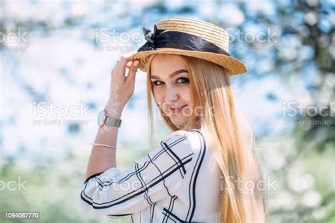 근접 촬영 카메라 웃 긴 머리를 가진 효과적인 여자의 초상화 밀 짚 모자를 들고 젊은 세련 된 금발 꽃 식물에 대한 스톡 사진