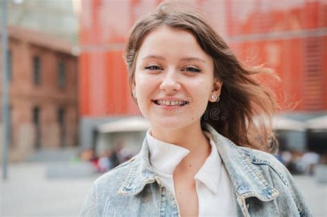 Young Woman Smiling And Looking At Camera Outdoors Wearing Casual