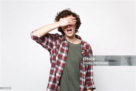 캐주얼에 충격 젊은 남자의 초상화는 입을 열어 스튜디오에서 흰색 벽 배경에 고립 된 손으로 눈을 덮고 사람들은 진심으로 감정