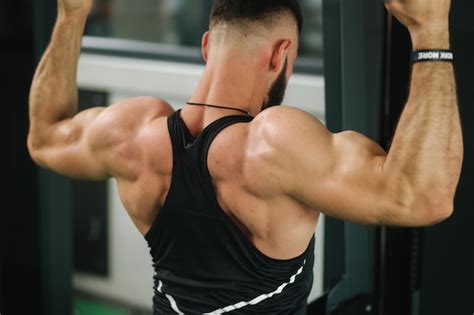 Um jovem atleta treina na academia mostra os músculos das costas e do