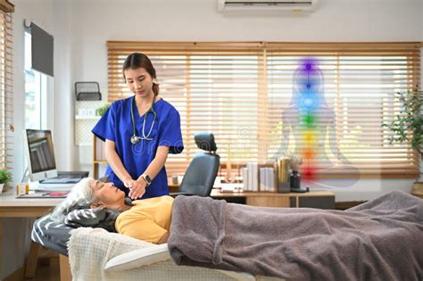 Senior Woman Having Reiki Healing Treatment With Therapist Alternative