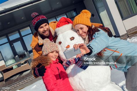 겨울 방학 눈사람이 쾌활하게 미소와 함께 스마트 폰에 셀카를 복용 집 근처에 서 야외에서 함께 가족 시간 3 명에 대한 스톡 사진 및 기타 이미지 Istock