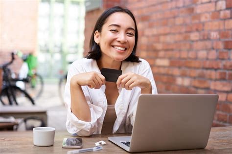 Premium Photo Happy Young Asian Female Sitting With Laptop And Showing Credit Card Paying