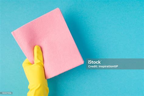 빈 공간이있는 고립 된 파스텔 블루 배경에 분홍색 비스코스 냅킨을 들고 있는 노란색 고무 장갑의 핸드 사진 상단 보기 사진 가사