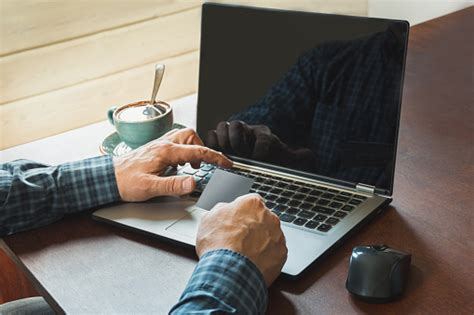 블랙 커피 한잔과 함께 사무실에 나무 테이블에 앉아 노트북을 사용 하 여 카드를 들고 남자의 손의 측면 보기 샷 닫습니다 개념에