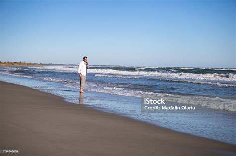 느슨한 흰색 셔츠와 넥타이와 롤업 바지와 중 년 기업 남자는 침착 하 게 자신의 어깨에 코트와 해변에서 맨발로 걷기 걷기에 대한 스톡 사진 및 기타 이미지 Istock