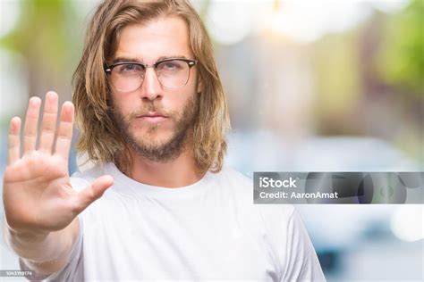 중지 하 고 격리 된 배경 위에 긴 머리 착용 안경 잘생긴 젊은이 손의 종 려를 가진 노래 얼굴에 부정적이 고 심각한 제스처와 경고 식입니다 거절에 대한 스톡 사진 및 기타