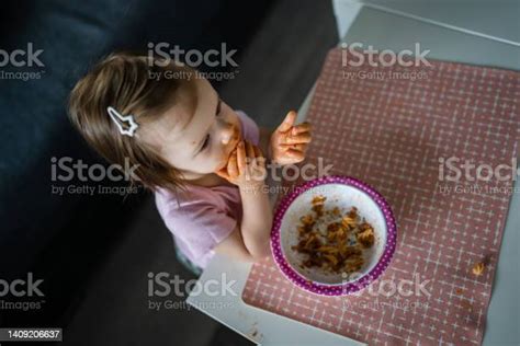 한 소녀 작은 백인 유아 여성 아이 딸이 집에서 테이블에서 혼자 식사를하면서 Tv를 보면서 그녀의 얼굴에 엉망진창으로 만드는