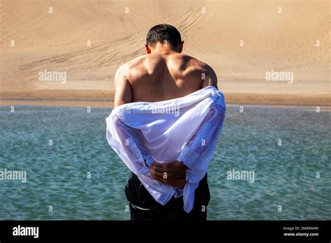 A Handsome Man Takes Off His White Wet Shirt At The Sea Muscular Back